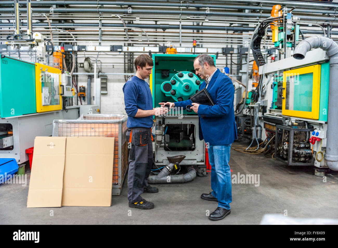 Manager and worker in plastics factory discussing production quality ...