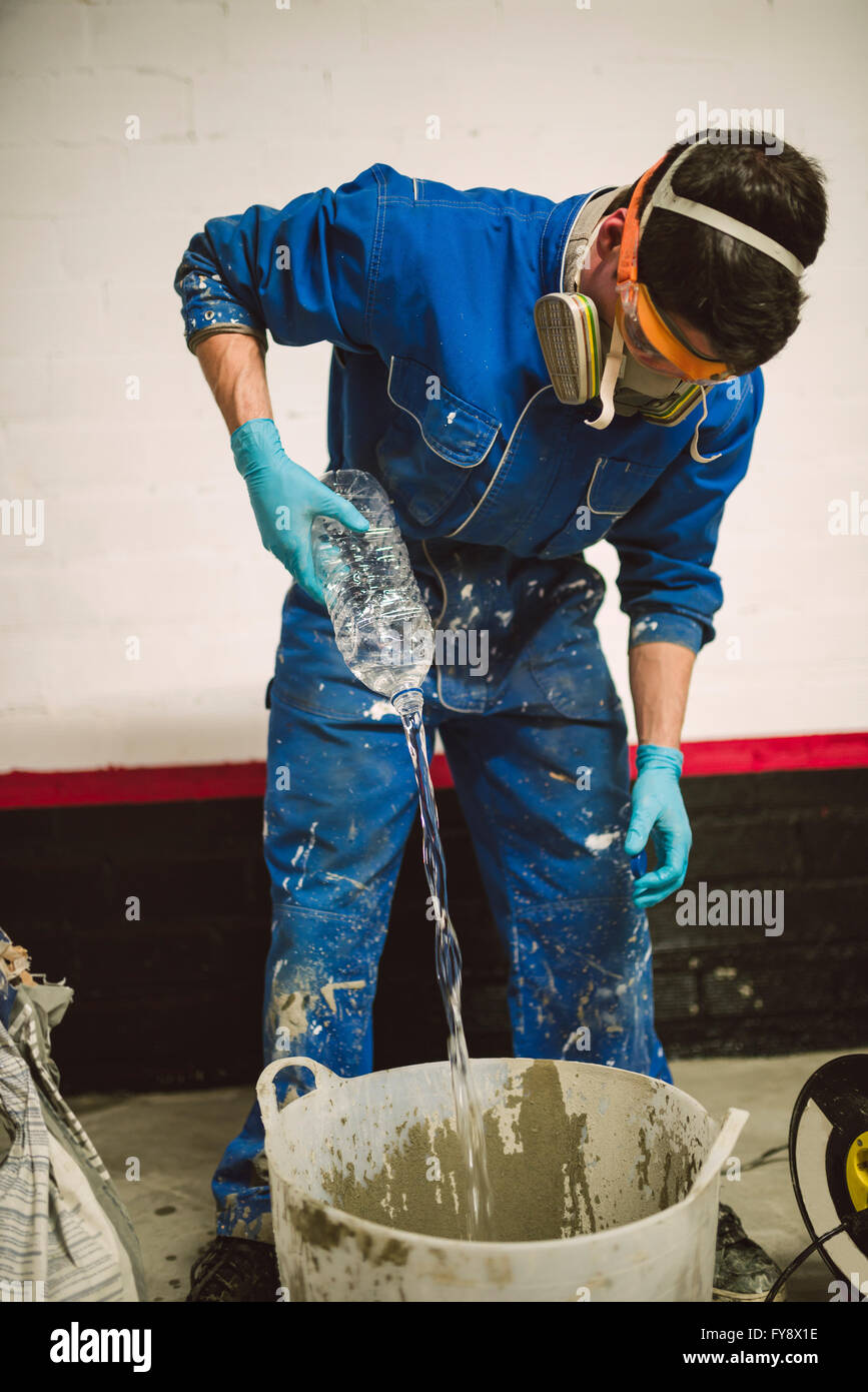 Bricklayer preparing cement in bucket, pouring water from bottle Stock ...