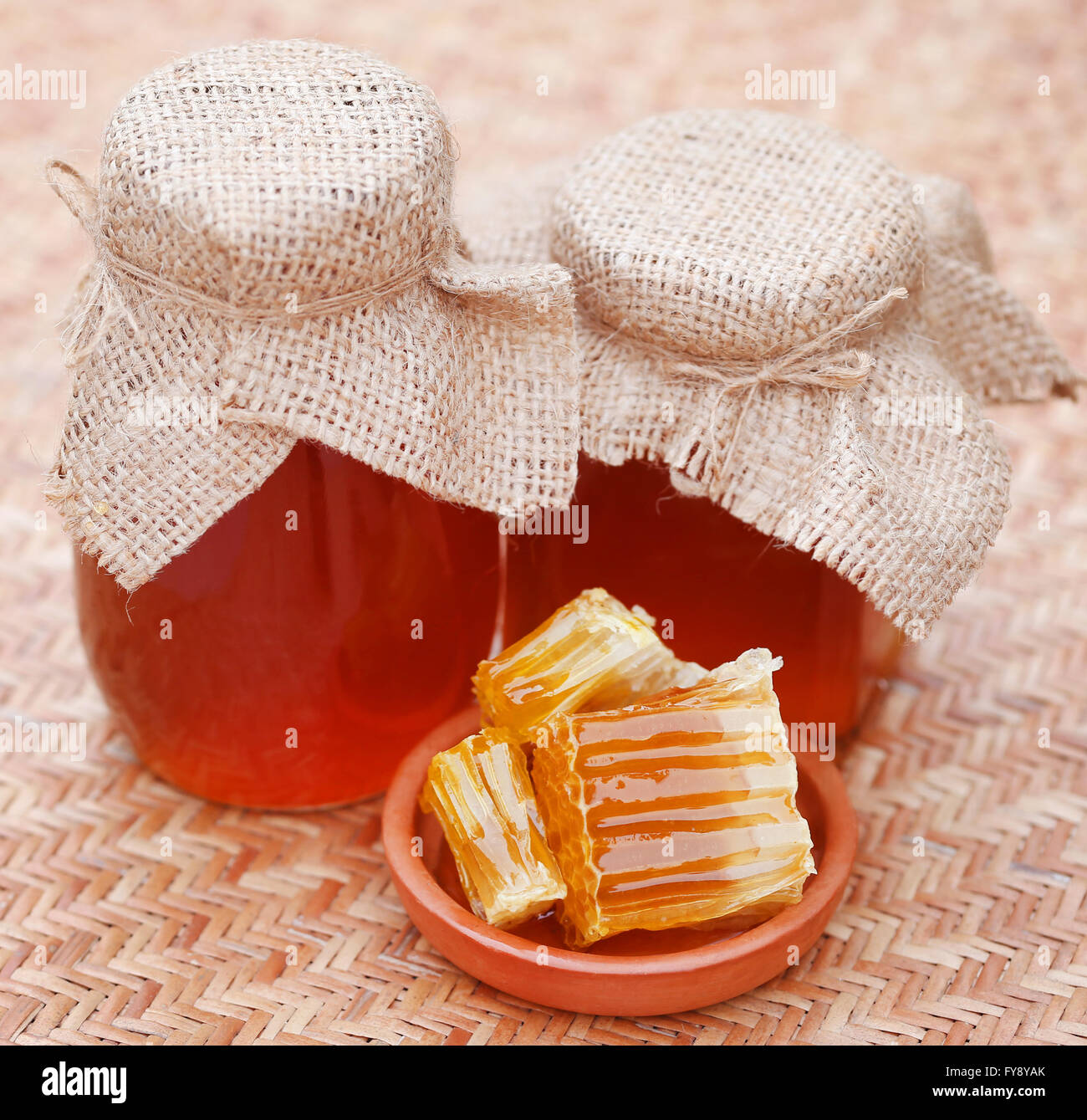 Honey in glass jar with bee hive on textured surface Stock Photo - Alamy