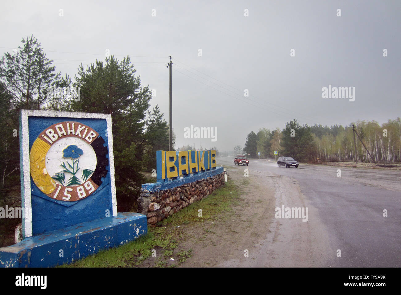 Cars travel past the town emblem along the access road to the town of ...
