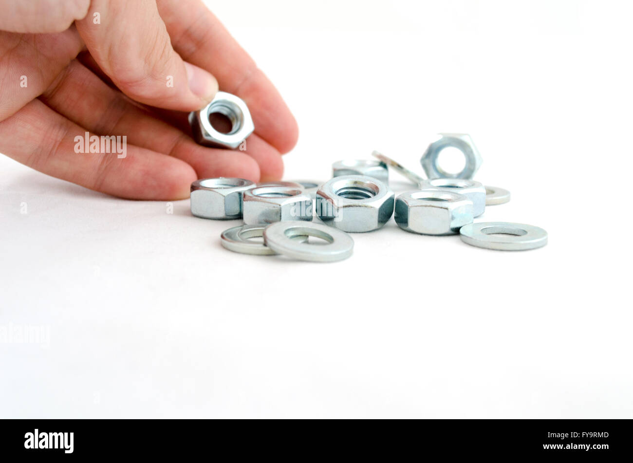 Several metal screw washers and nuts in human hand isolated on white ...
