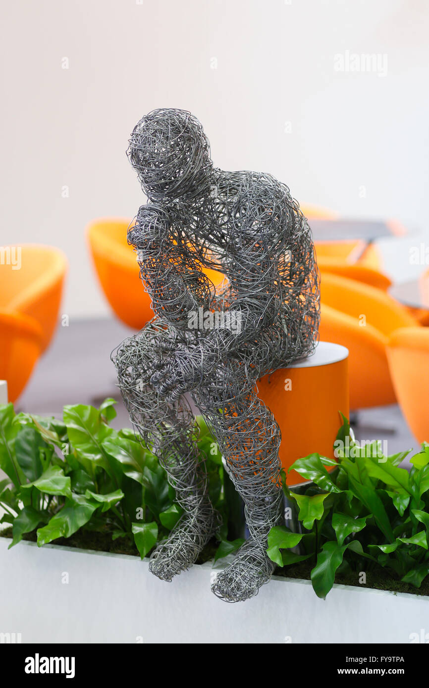 Wire figure of sitting man, grass and orange background Stock Photo - Alamy