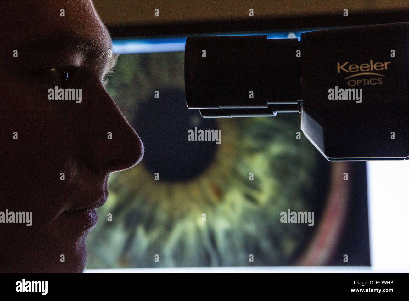 Optician looking at eye through microscope Pic Peter Devlin Stock Photo ...