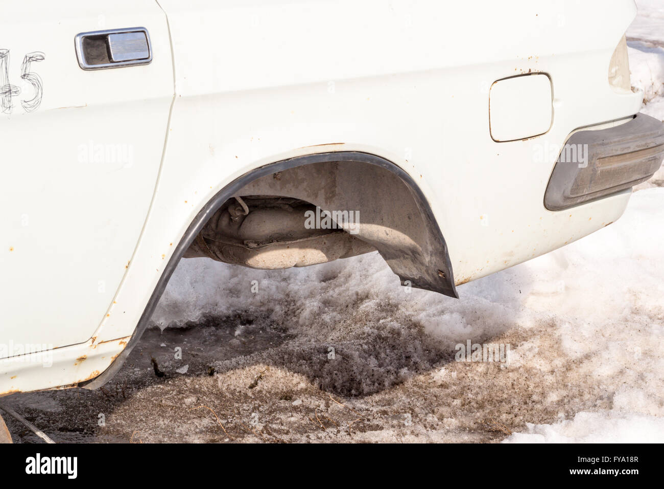 White car with a missing or stolen wheel showing just the empty wheel ...