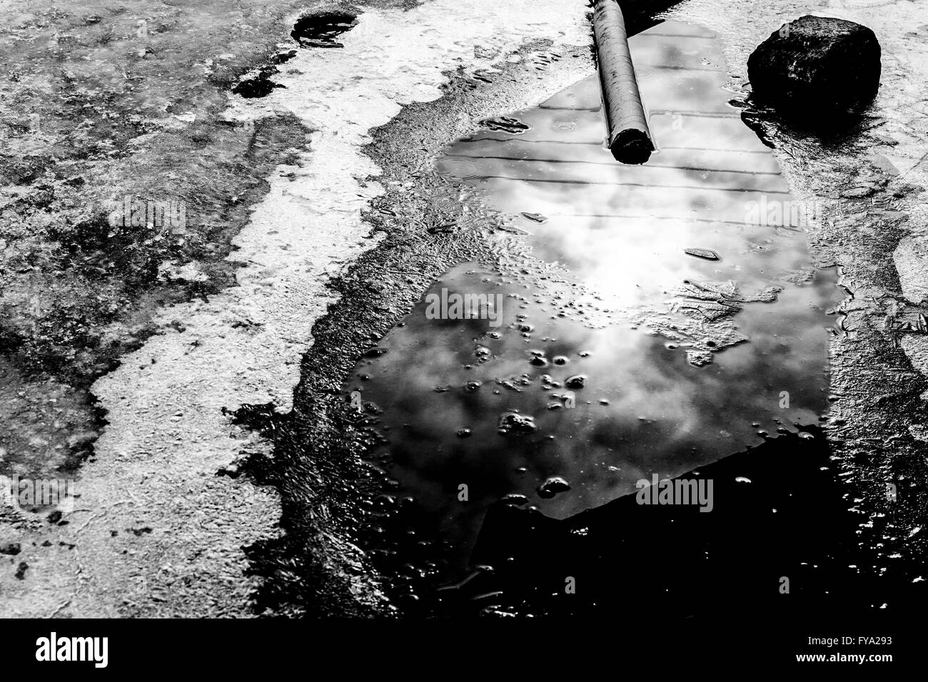 Rain puddle black and water abstract reflection with natural sunlight ...
