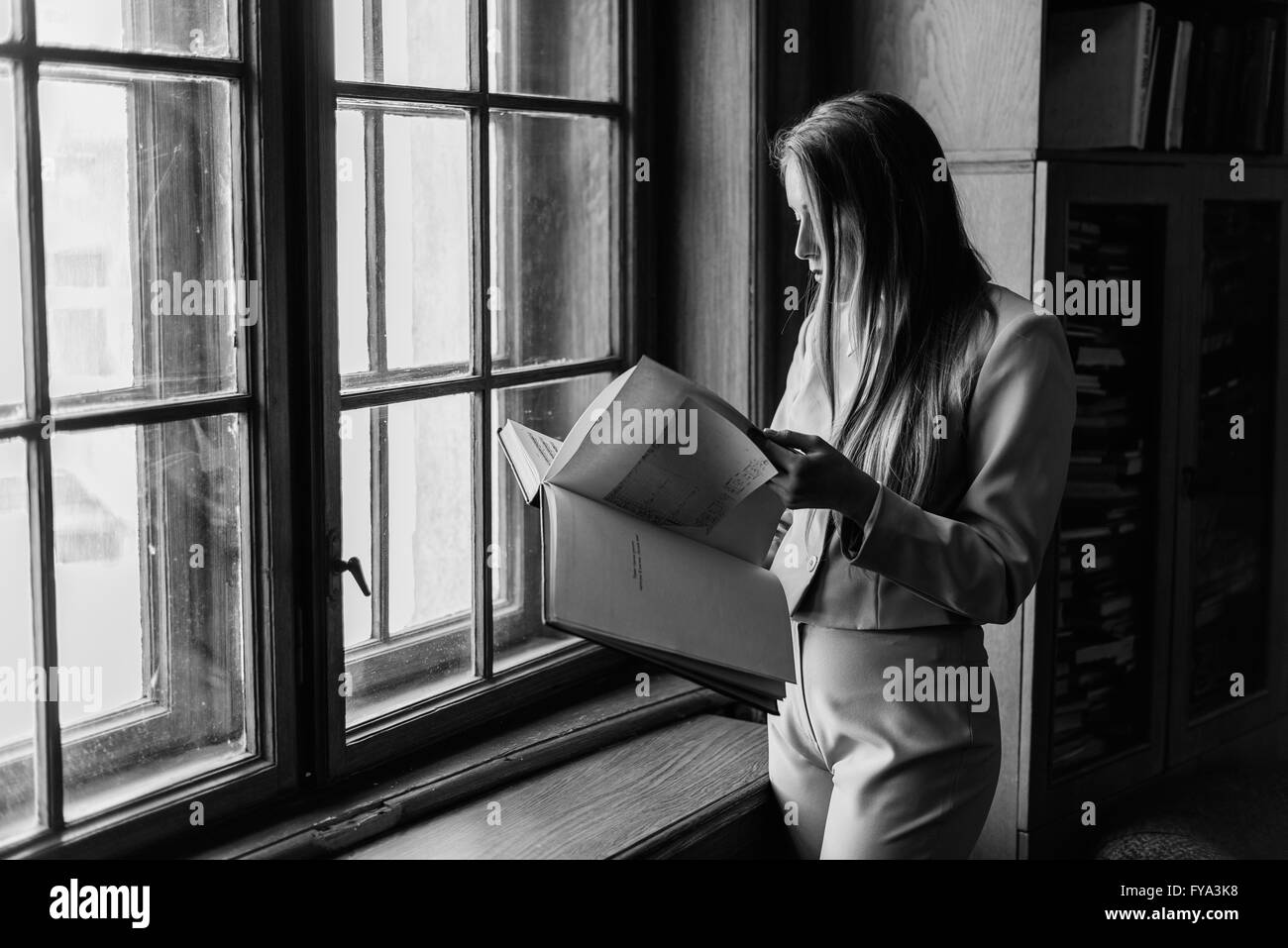 Beautiful stylish young girl reading a book near the vintage window in ...