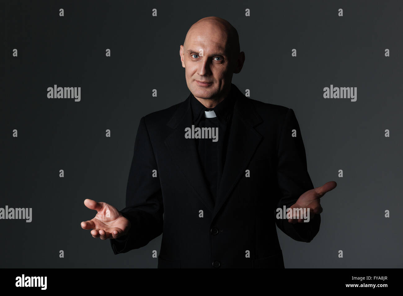 Catholic priest standing and doing welcome gesture over black ...
