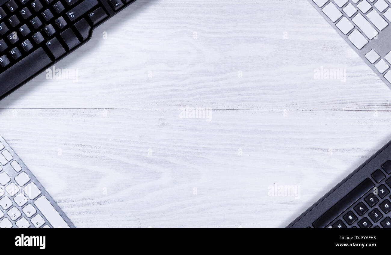 Top view of computer keyboards on all corners of white desktop Stock ...