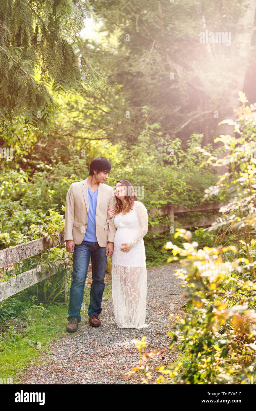 Expecting mom and dad, front to camera, walking on path through the ...