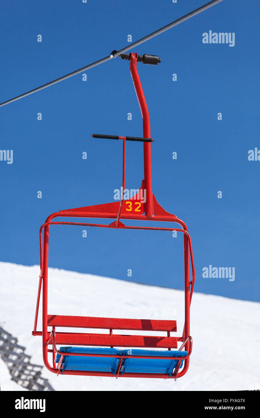 empty single chair of ski lift going down from the peak of the mountain ...
