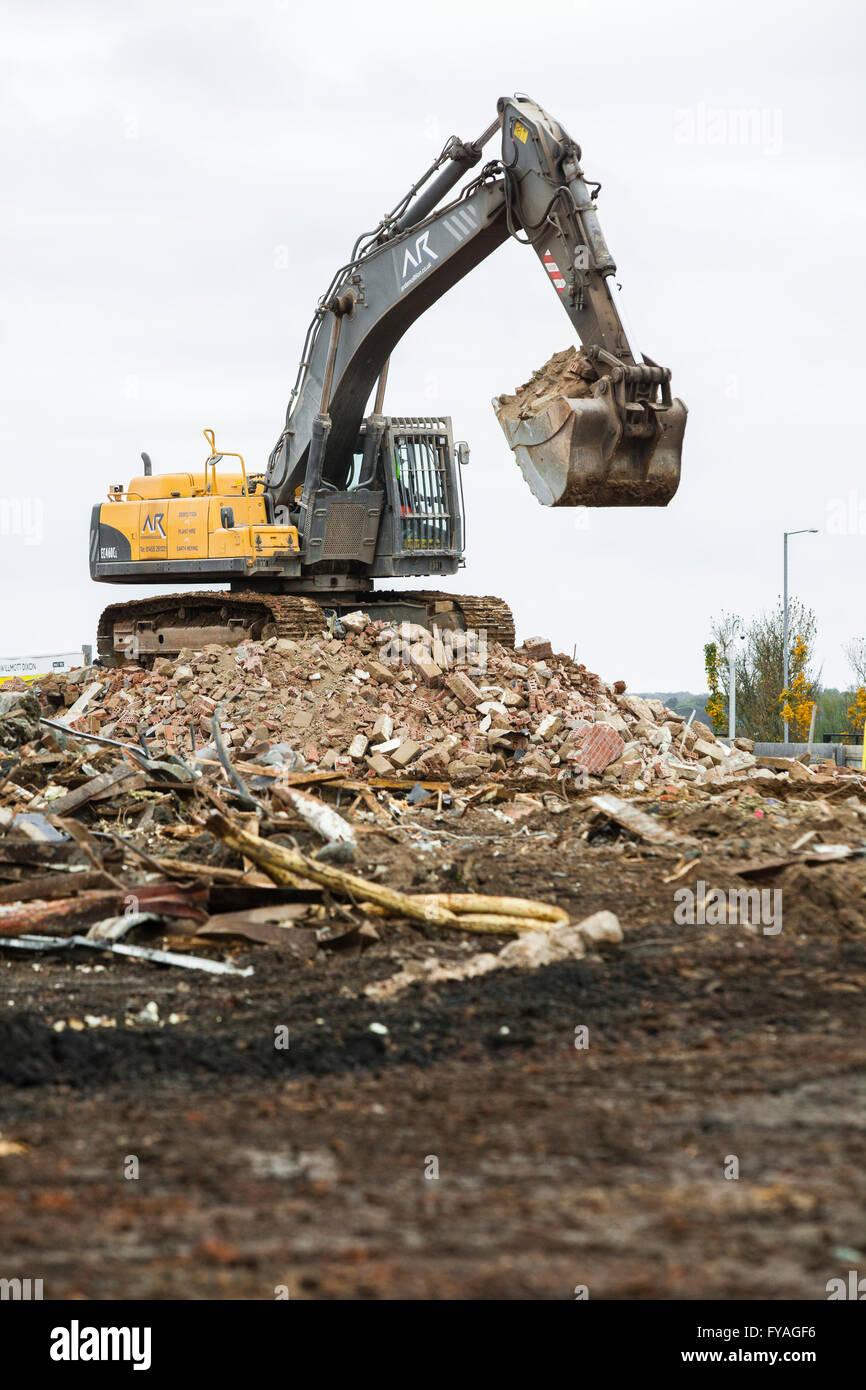 A demolition site in UK. Heavy plant machines demolishing an old school ...
