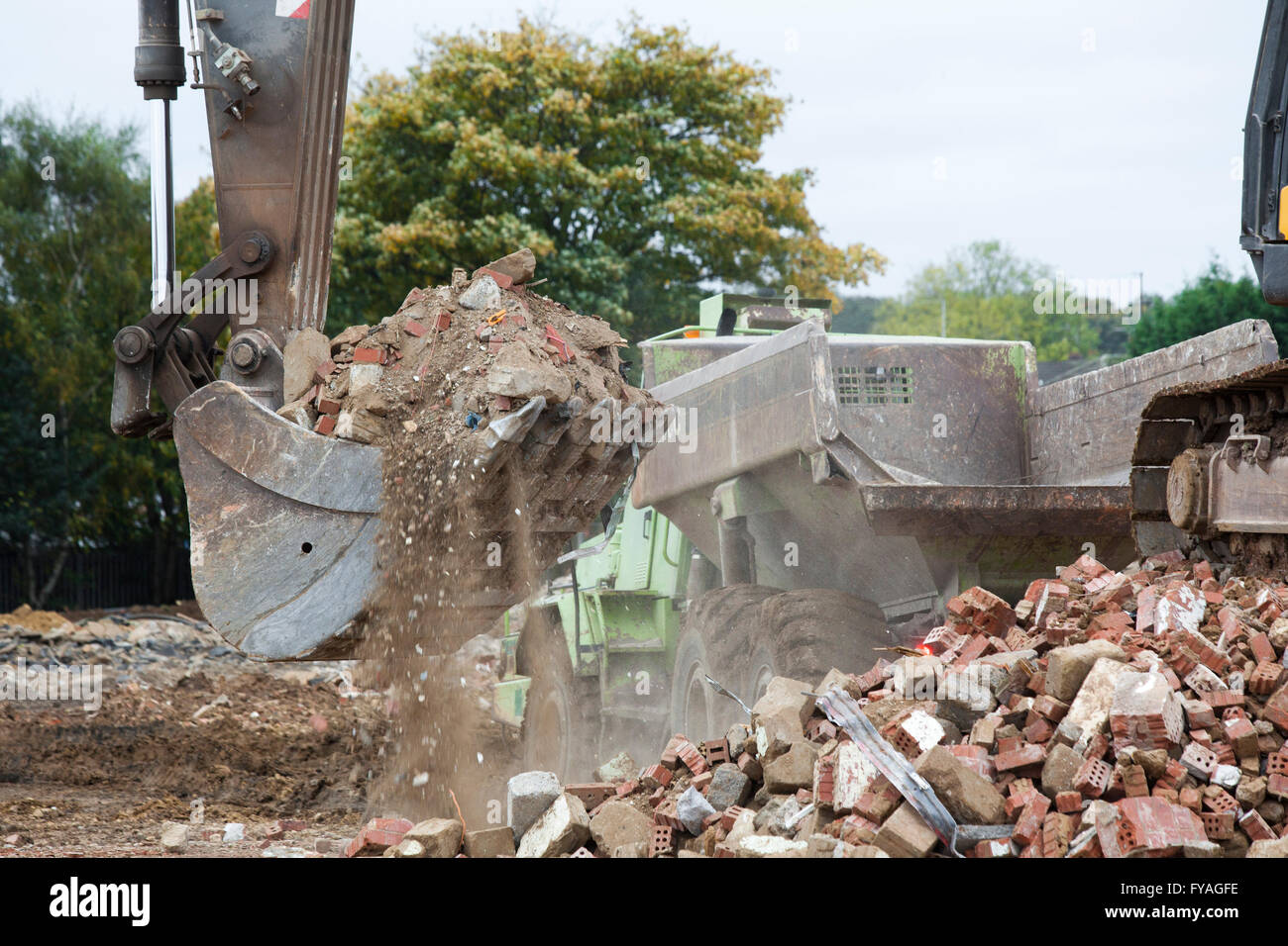 A demolition site in UK. Heavy plant machines demolishing an old school ...