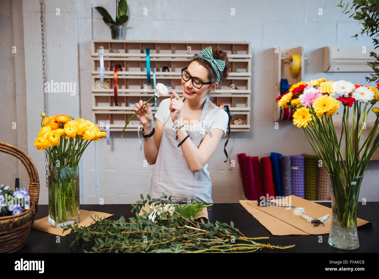 Happy cute young woman florist enjoying white rose in flower shop Stock ...