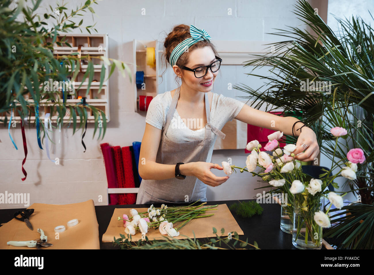 Smiling attractive young woman florist working and making bouquet in ...