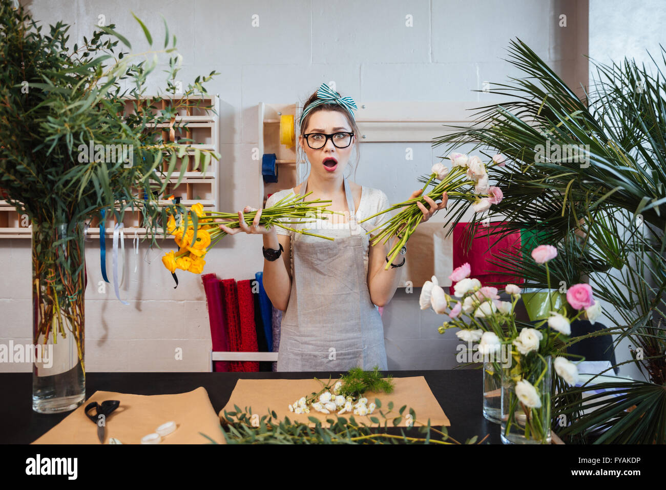 Amazed shoked young woman florist designing bouquet and holding two ...