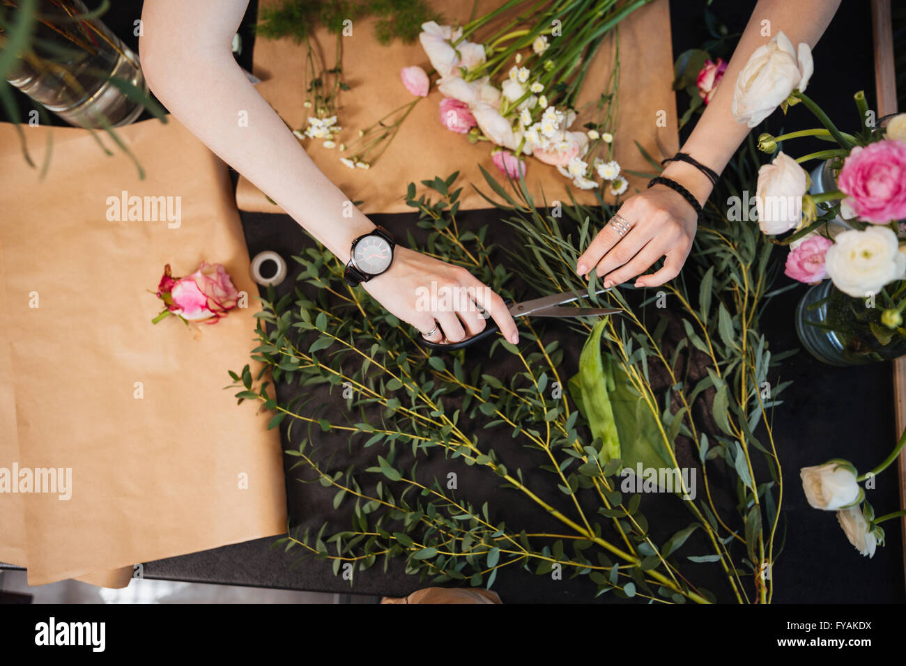 Top view of hands of young woman florist cutting flowers with scissors ...