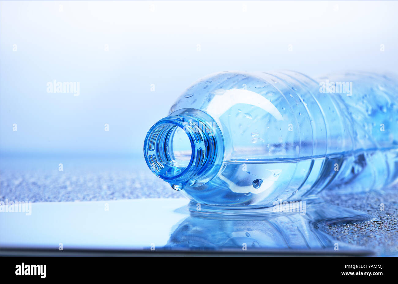 Drop of water falling from plastic bottle with reflection on white and ...