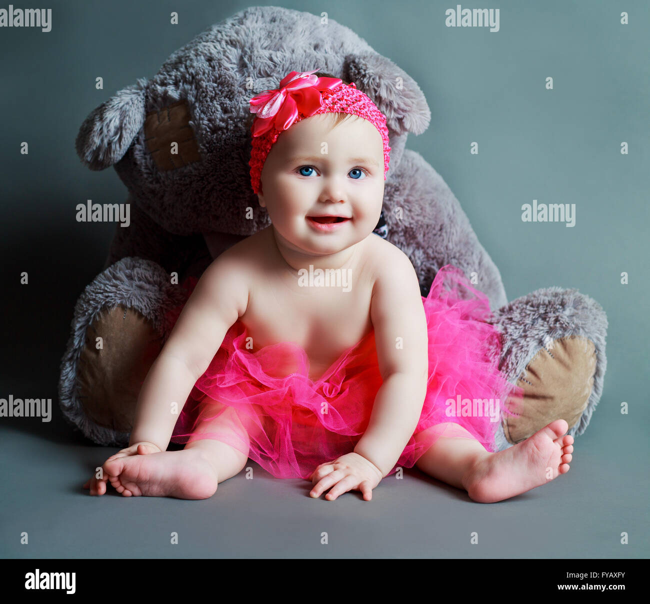 adorable six months old baby with a toy against gray studio background ...