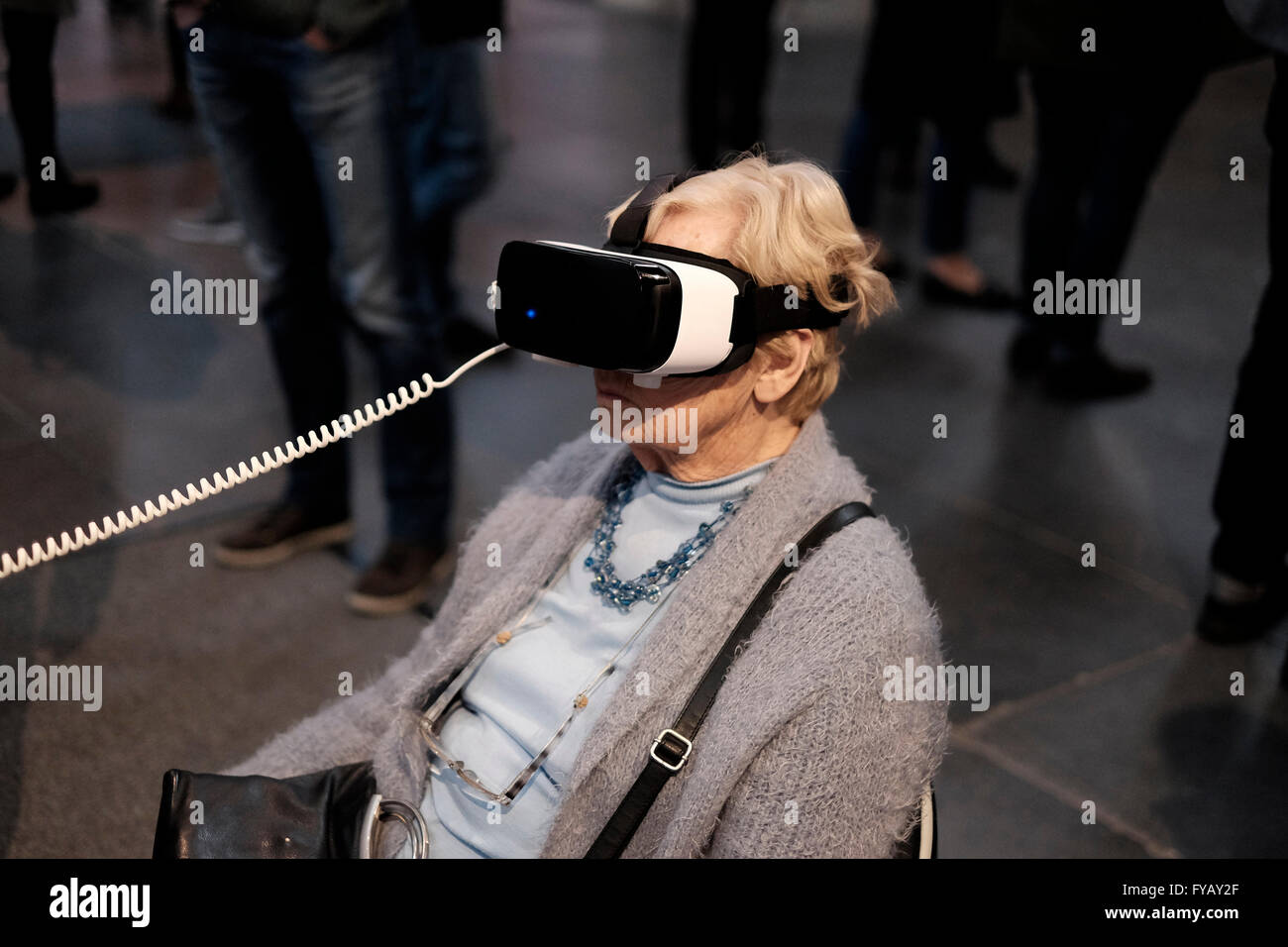 An elderly visitor watches VR content through virtual reality goggles ...
