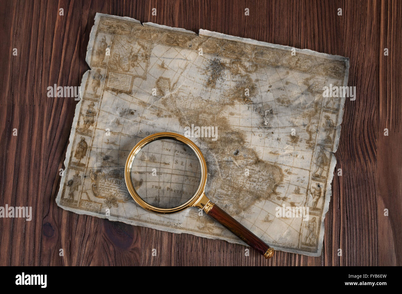 Old map and magnifying glass on a wooden background Stock Photo - Alamy