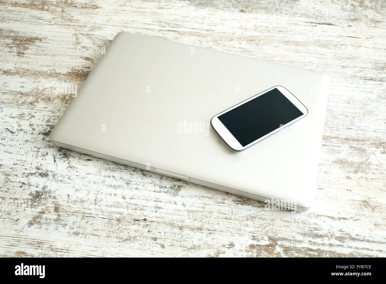 A Smartphone and a switched off laptop computer on a wooden Desktop ...
