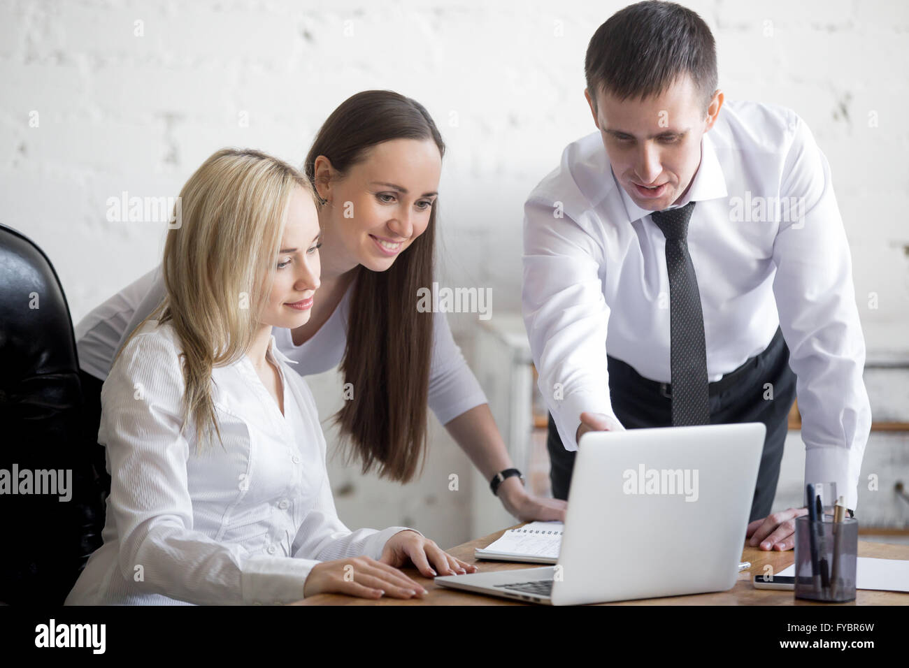 Teamwork concept. Group of three smiling young people working on ...
