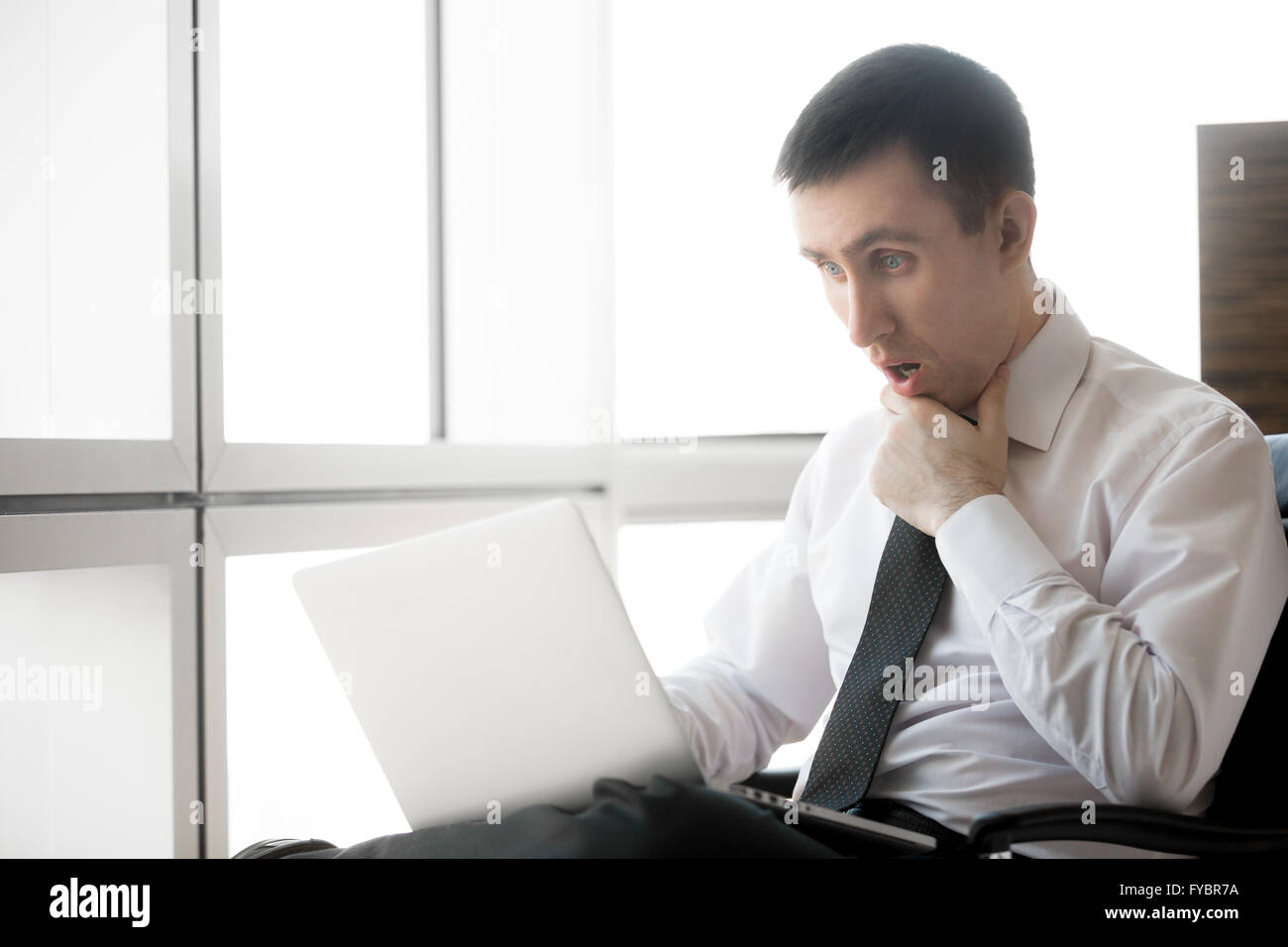 Handsome young businessman sitting in his office using laptop ...
