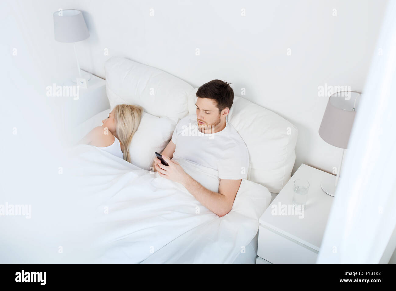 man texting message while woman is sleeping in bed Stock Photo - Alamy