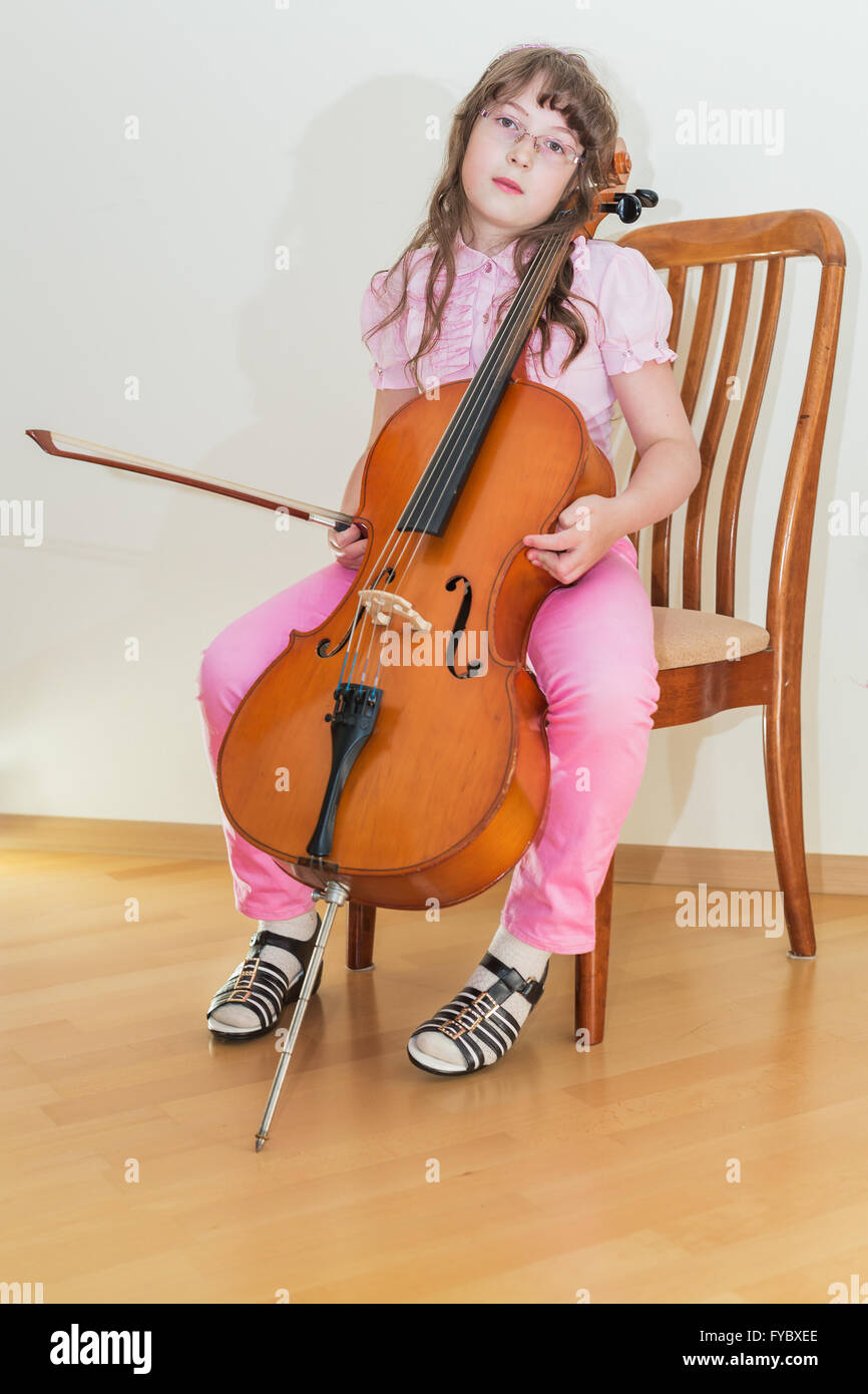 Pretty young girl practice playing cello sitting on chair Stock Photo ...