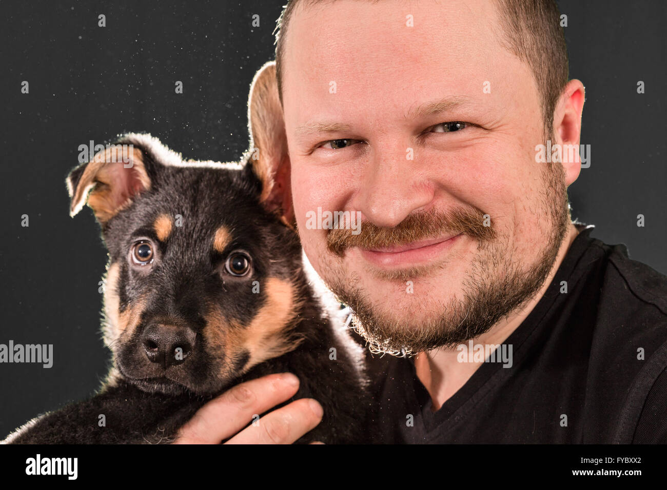 Portrait of a man with puppy dog studio low key Stock Photo - Alamy