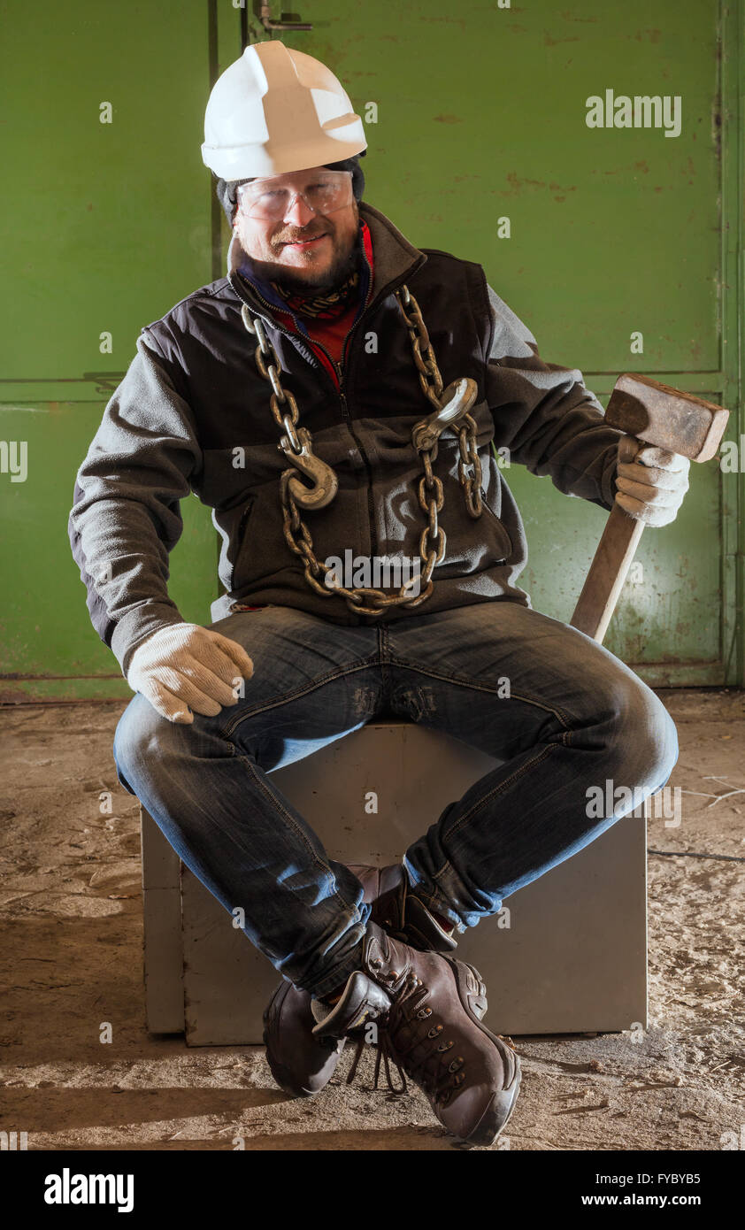 Tough worker in safety helmet with iron chain and sledgehammer Stock ...