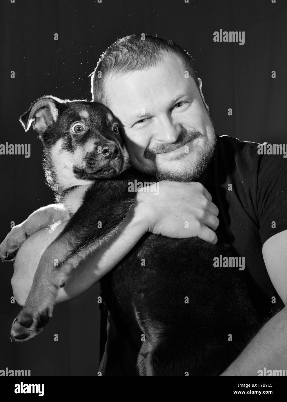 Portrait of a man with puppy dog studio low key Stock Photo - Alamy