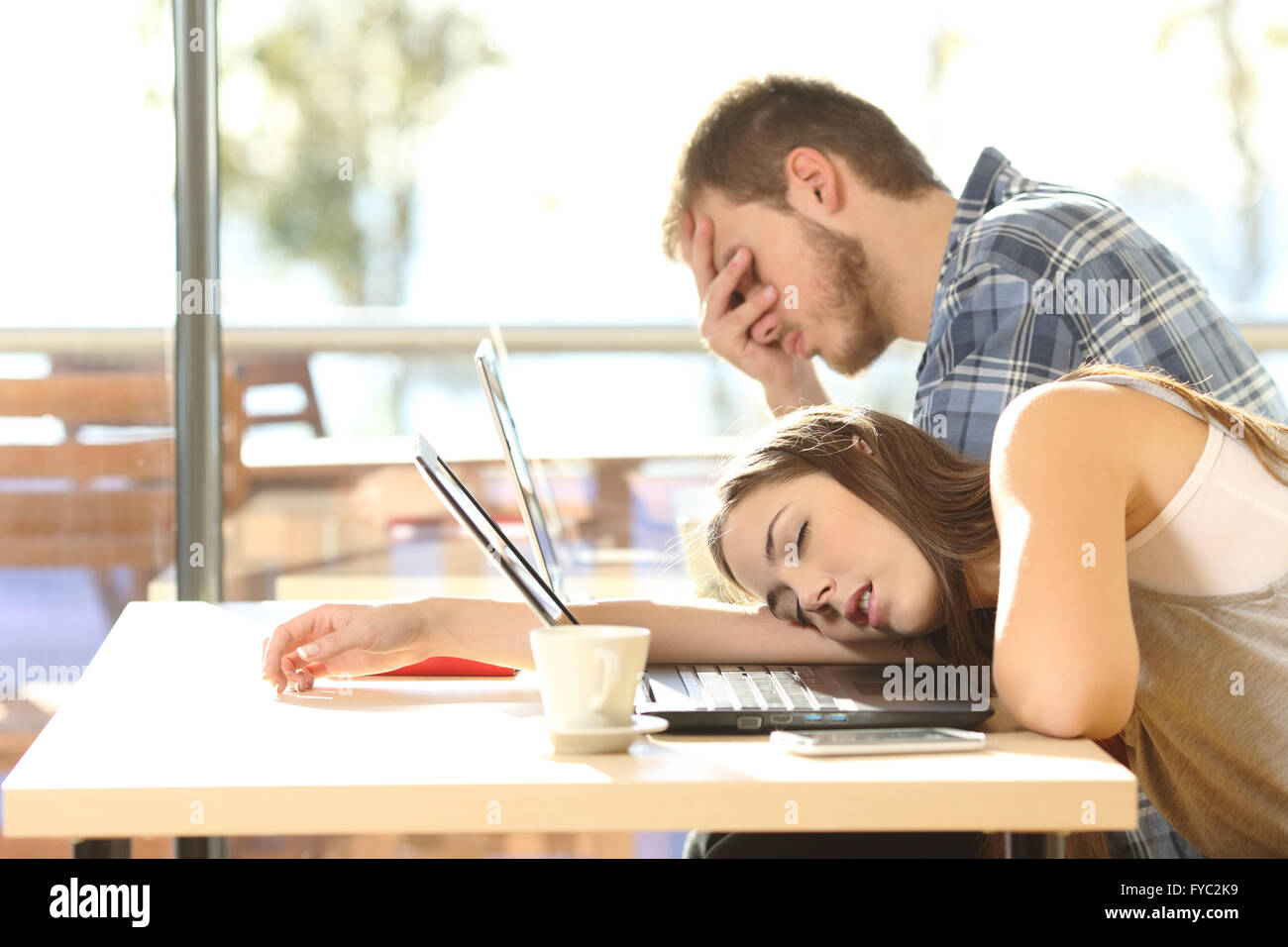 Side view of tired students surrendering to fatigue studying with ...