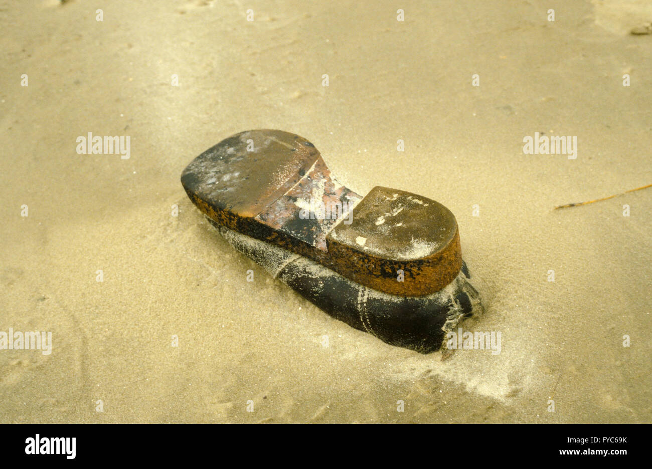 Old shoe in the sand as jetsam at the beach of the Danish isle Rømø ...