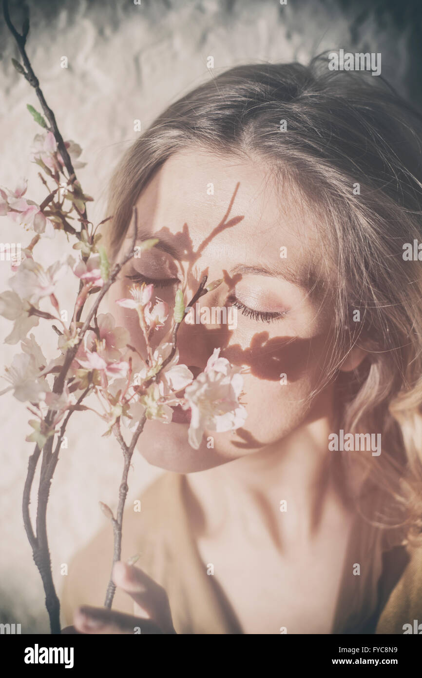 Beautiful young woman smelling flowers on the tree Stock Photo - Alamy