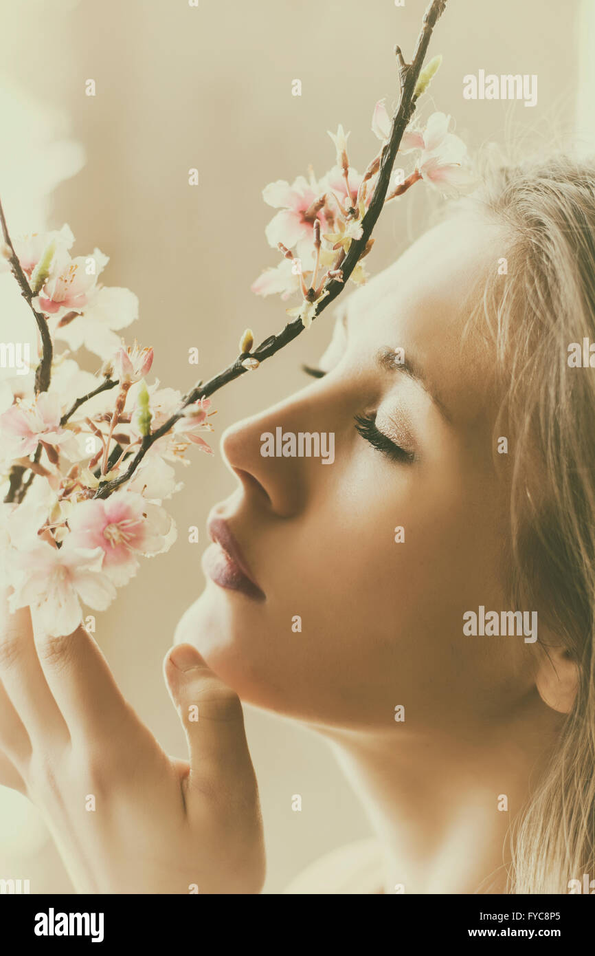 Beautiful young woman smelling flowers on the tree Stock Photo - Alamy