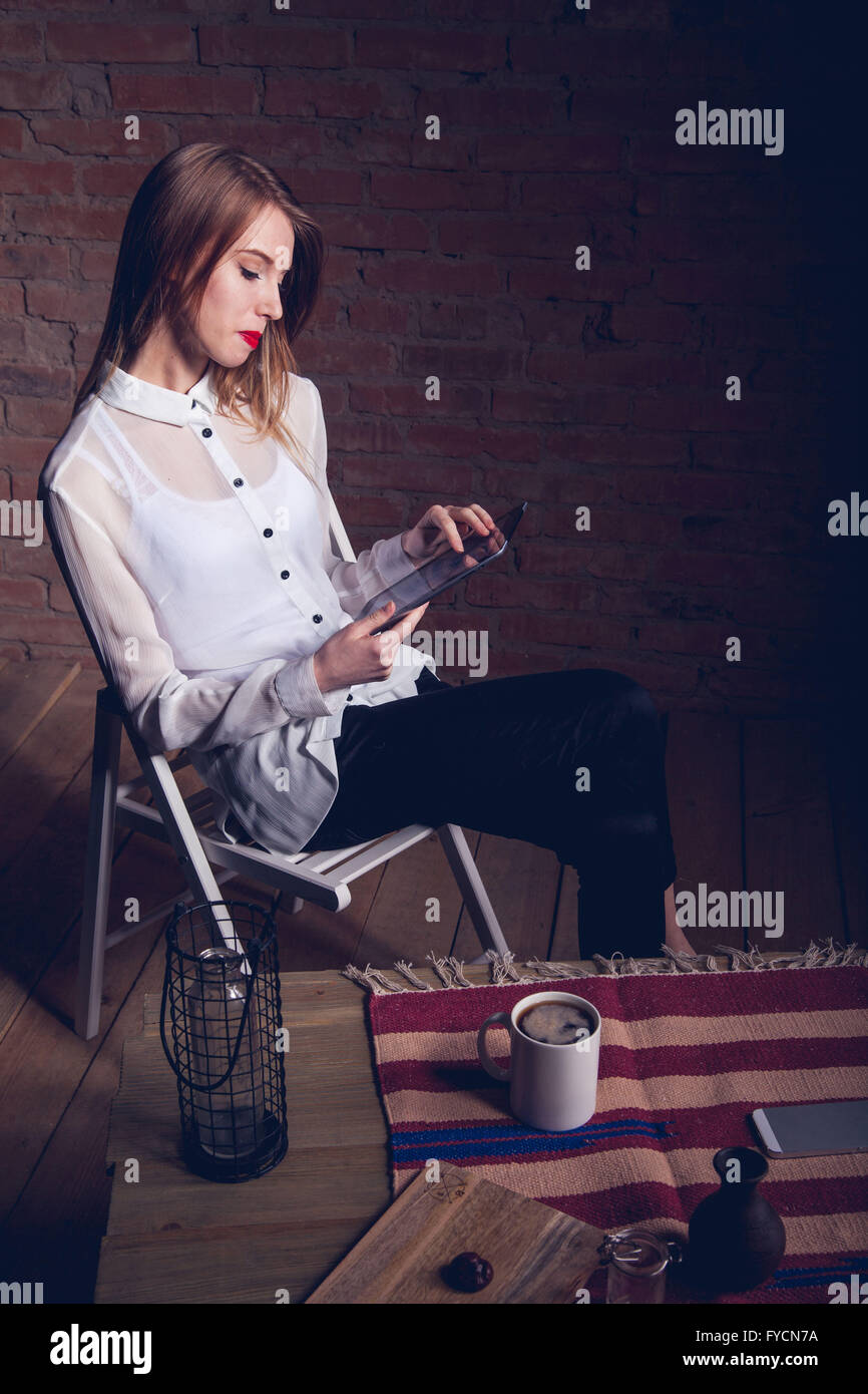 Beautiful girl working behind the plate at the table . Brick background ...