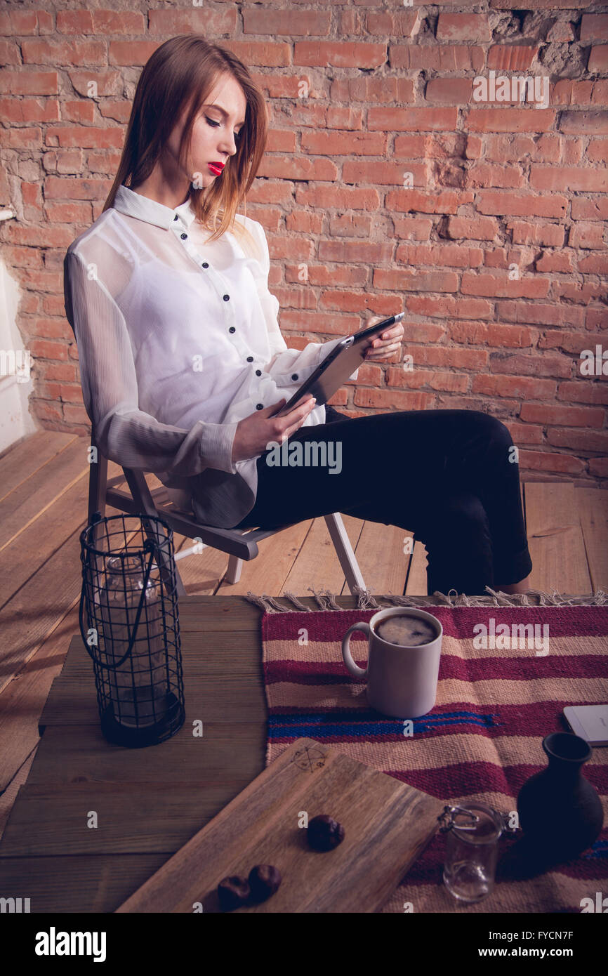 Beautiful girl working behind the plate at the table . Brick background ...
