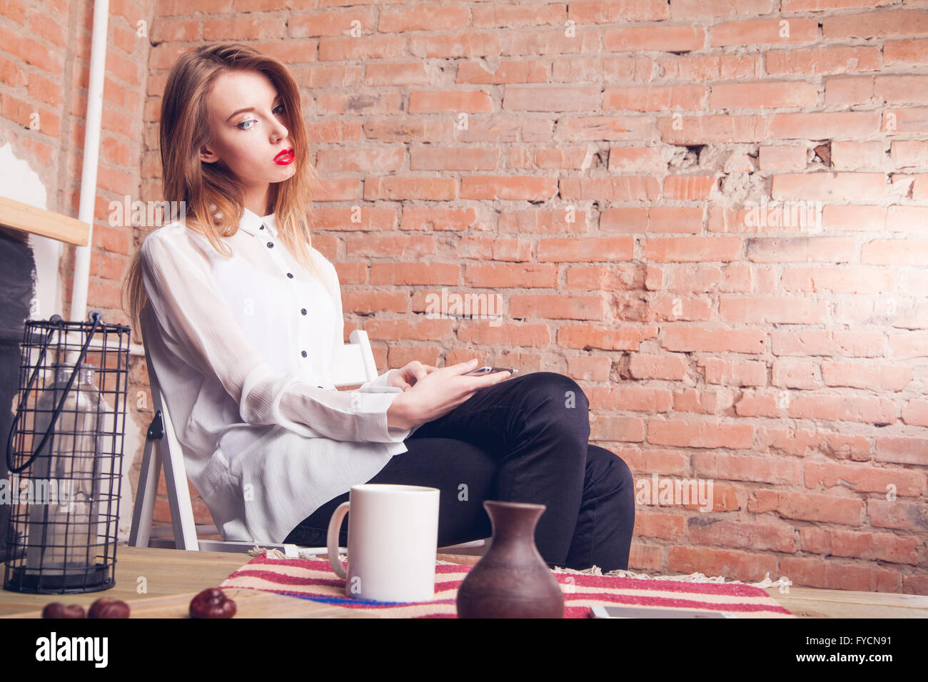 Beautiful girl working behind the plate at the table . Brick background ...