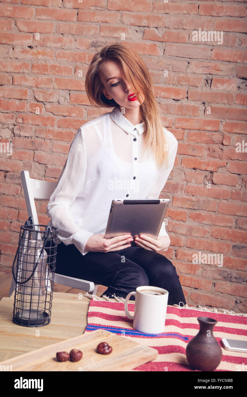 Beautiful girl working behind the plate at the table . Brick background ...