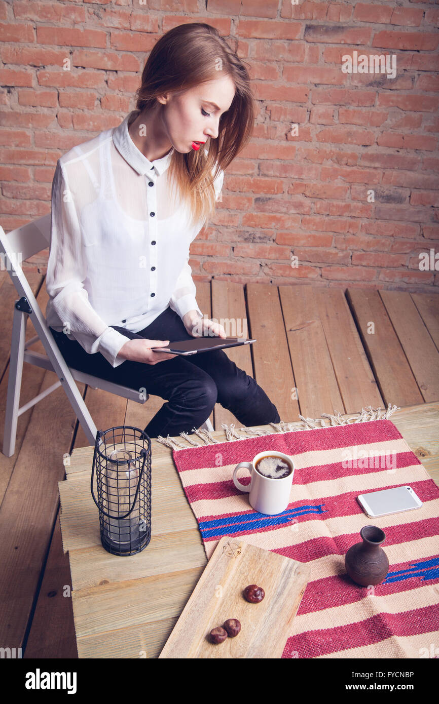 Beautiful girl working behind the plate at the table . Brick background ...