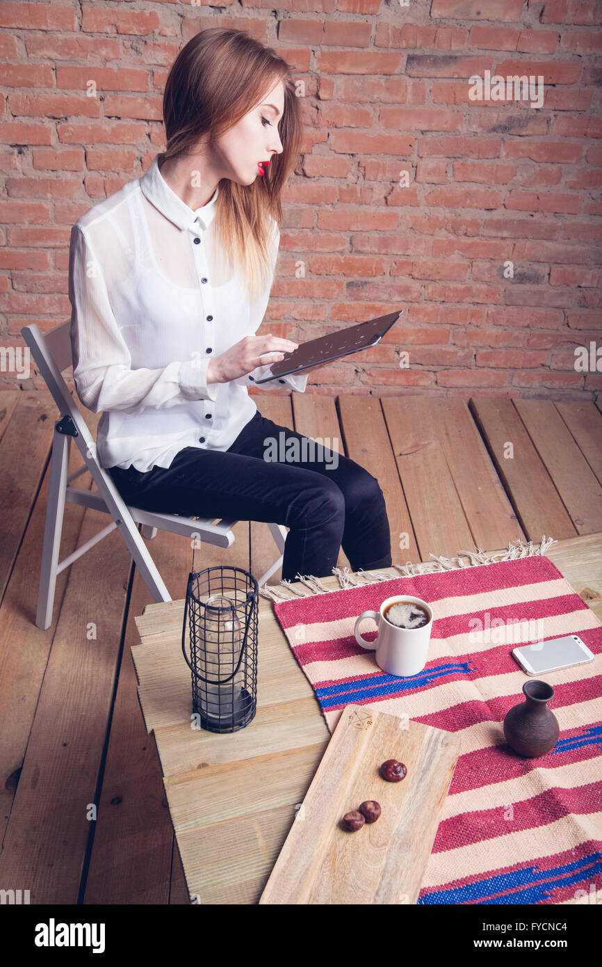 Beautiful girl working behind the plate at the table . Brick background ...