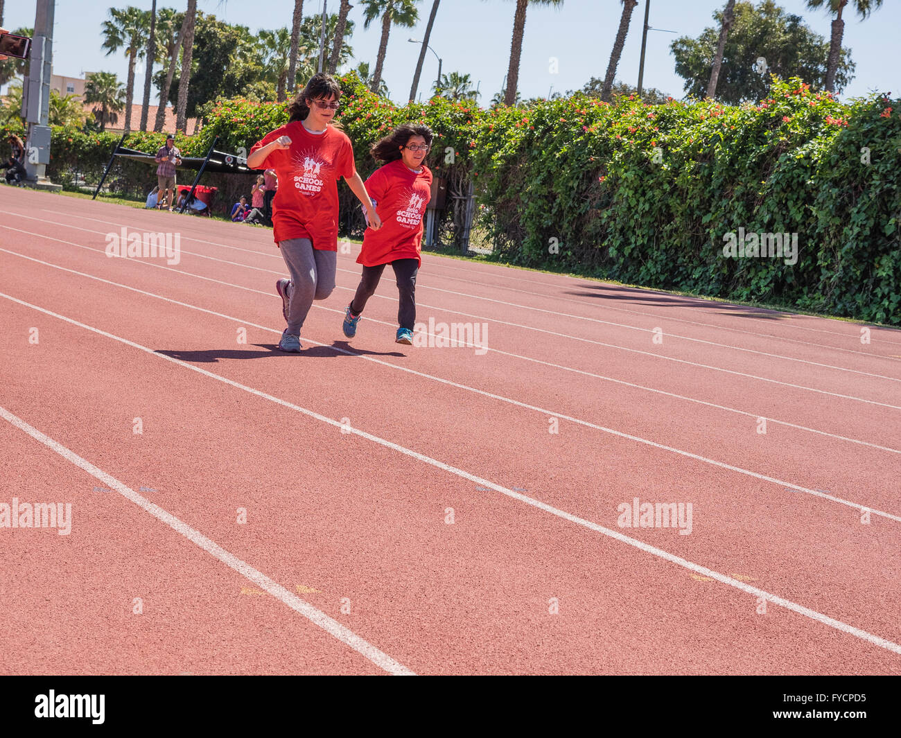 An adult helper helps a disabled girl race in a 50 meter race at the ...
