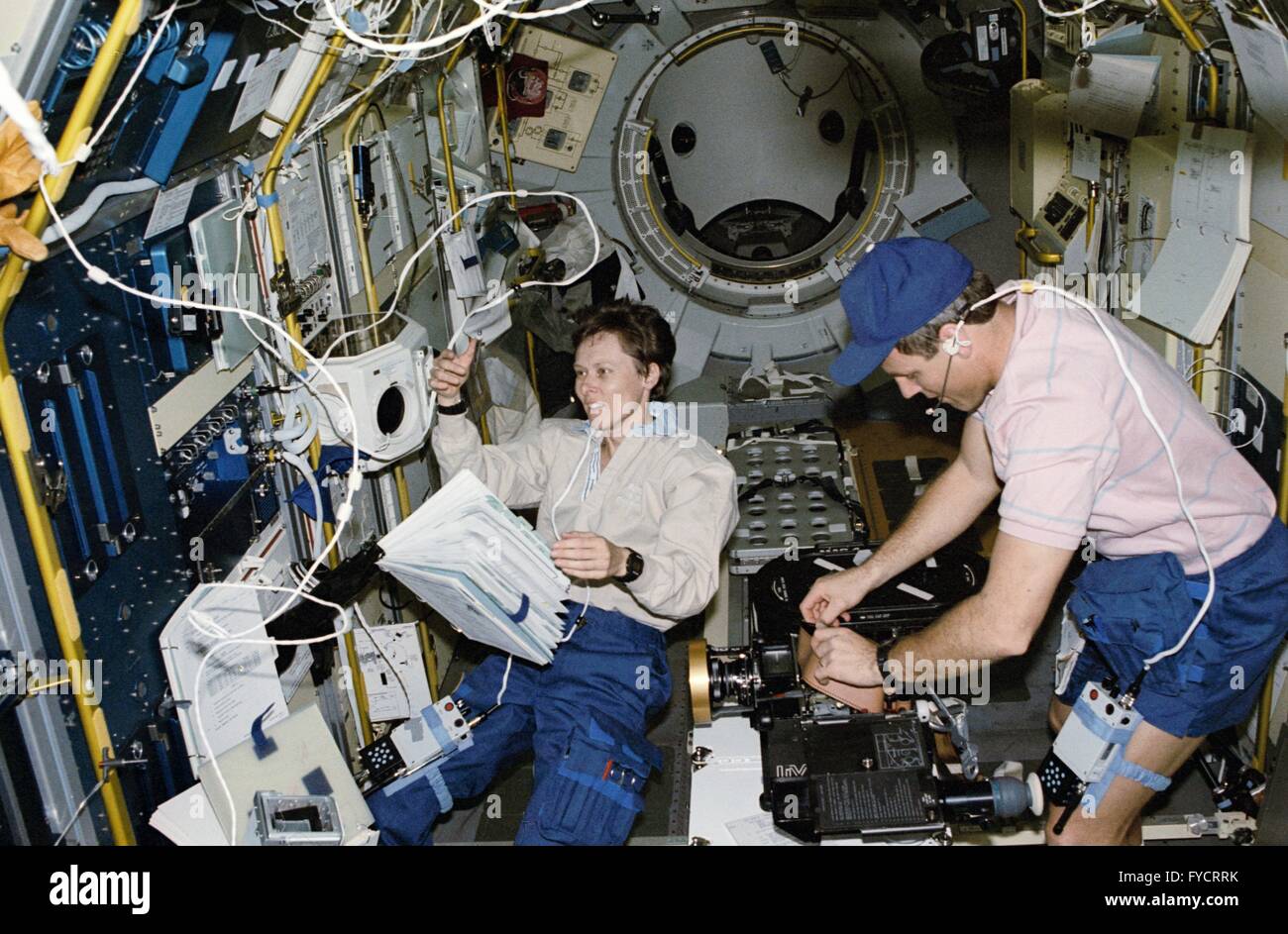 NASA astronaut Stephen Oswald, right, changes a film magazine on the ...