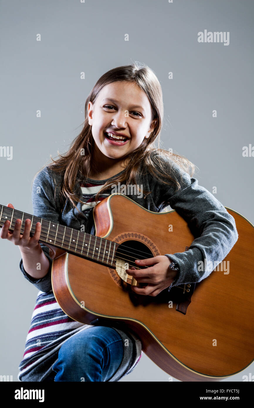 smiling girl playing acoustic classic wooden guitar smiling and singing ...