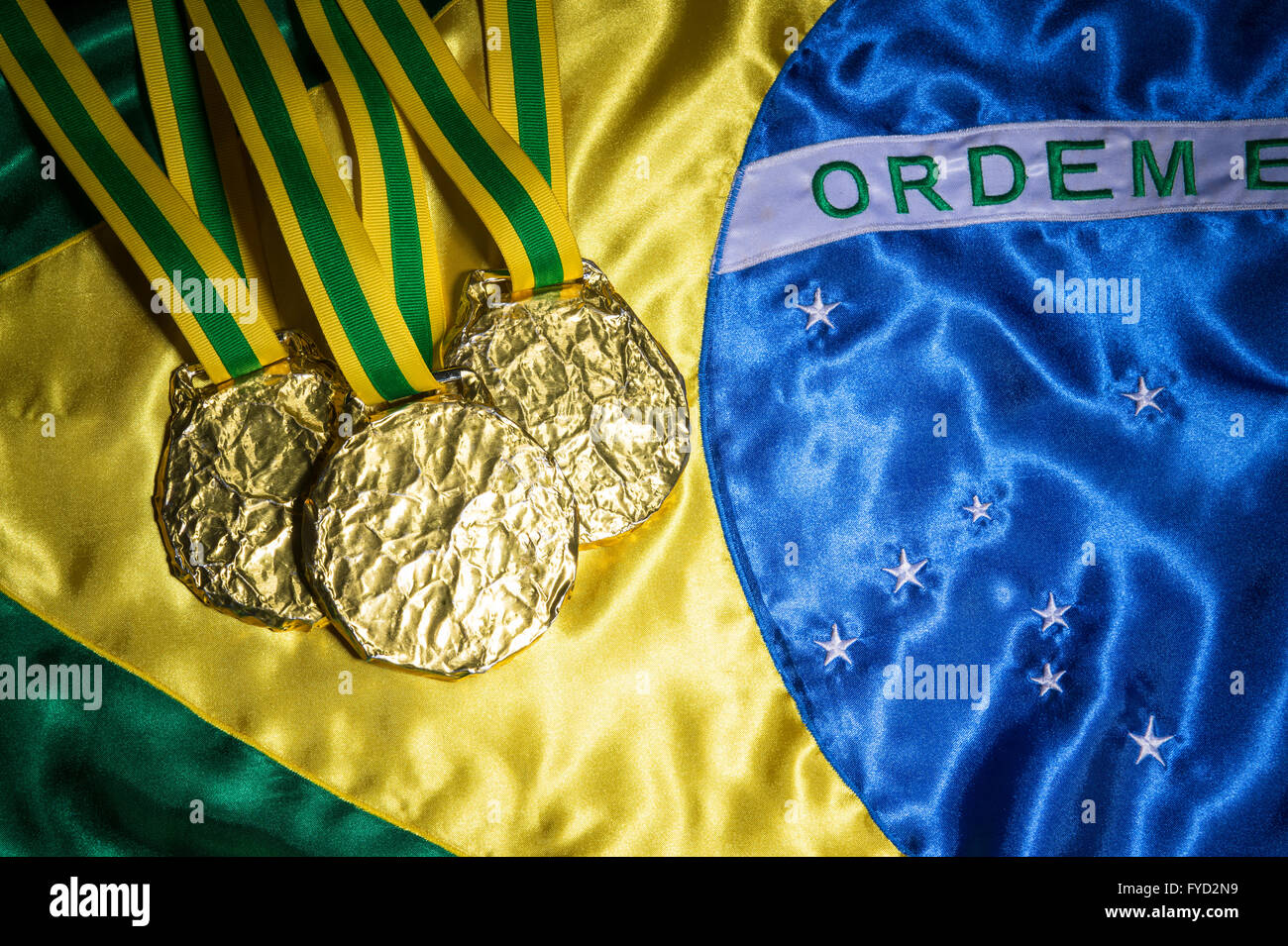 Three gold medals resting on shiny Brazil flag background with studio ...