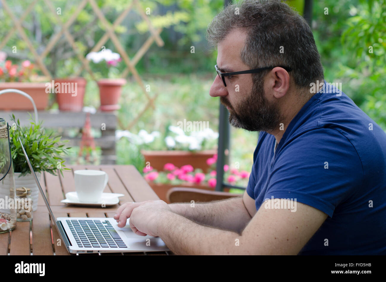 Man sitting on a bench outside and working on laptop Stock Photo - Alamy