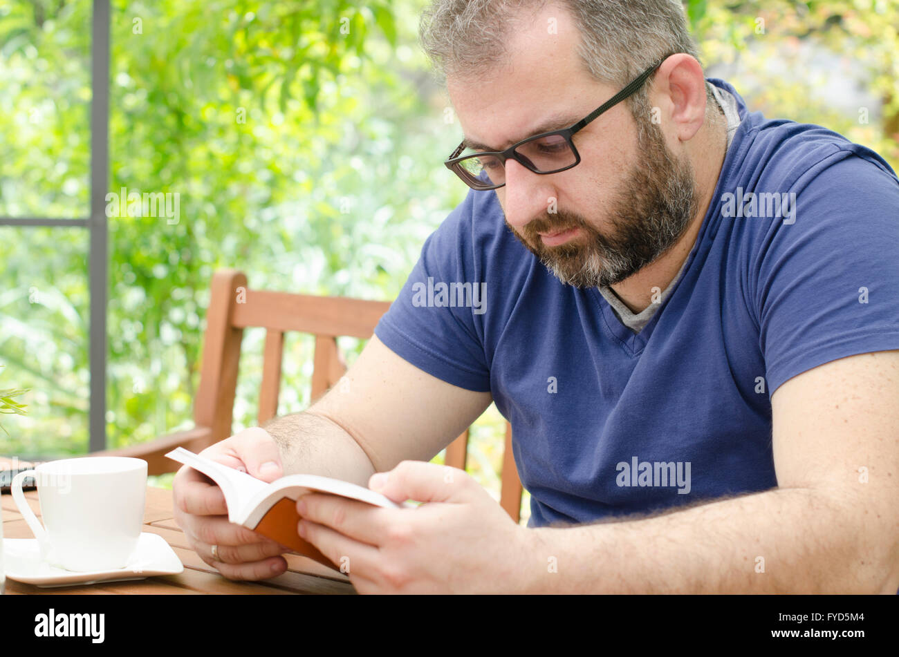 Man sitting on a bench outside and read a book Stock Photo - Alamy