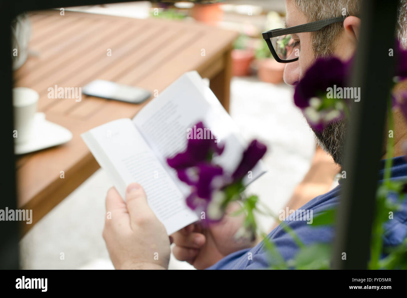 Man sitting on a bench outside and read a book Stock Photo - Alamy