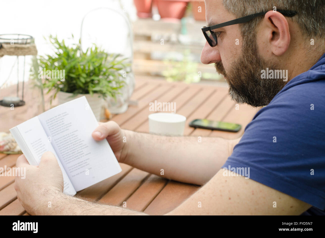 Man sitting on a bench outside and read a book Stock Photo - Alamy